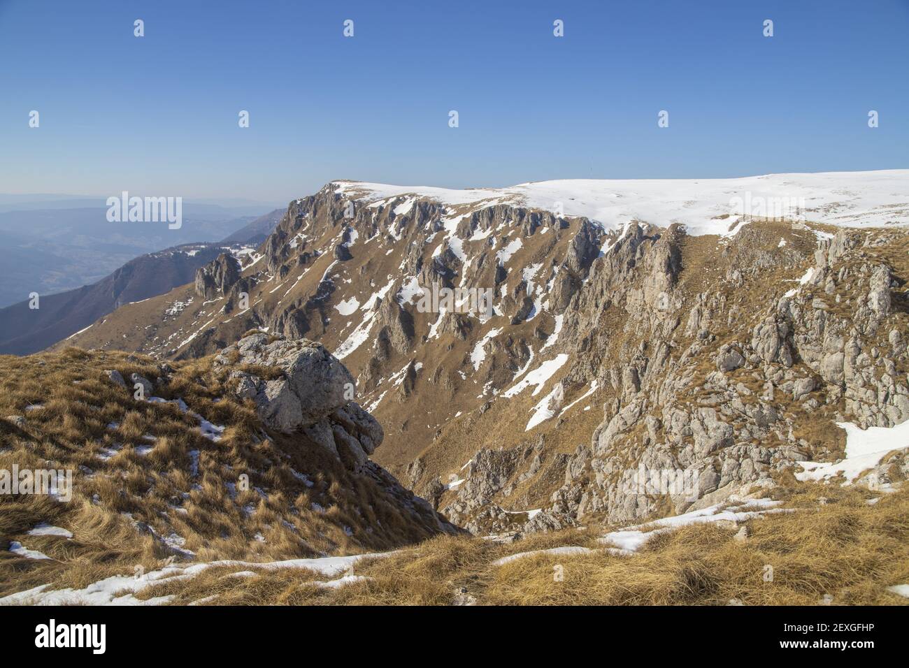A beautiful view of rocky cliffs covered in snow under a bright sky ...