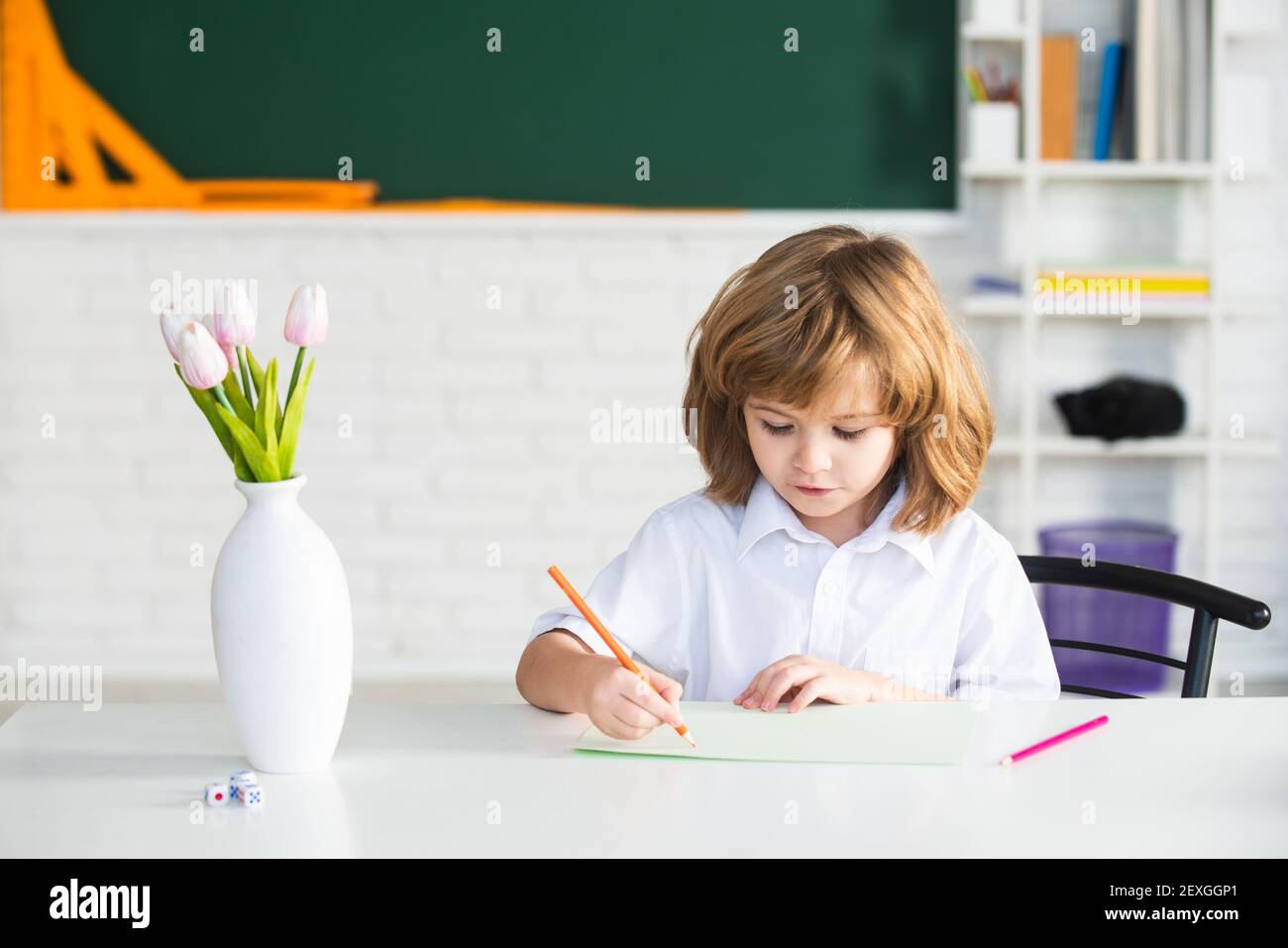 Schoolboy doing homework. School kid against green chalkboard. Gets ...