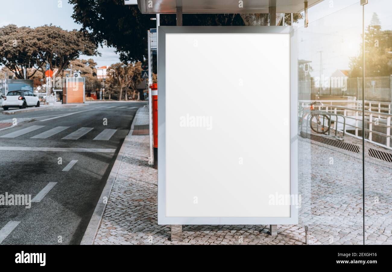A city glass bus stop with a mockup of a blank advert billboard inside ...