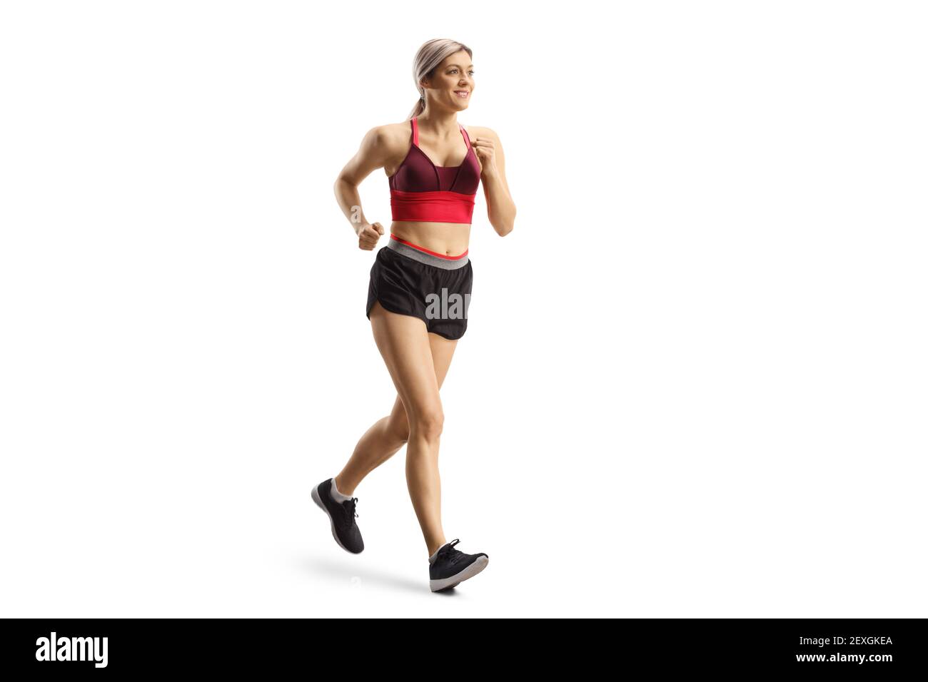 Full length shot of a blond young female in sportswear running isolated ...