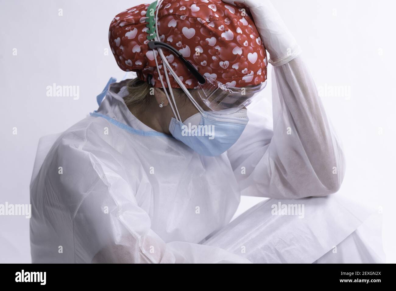 A young nurse wearing a protective medical uniform, mask, cap, and ...