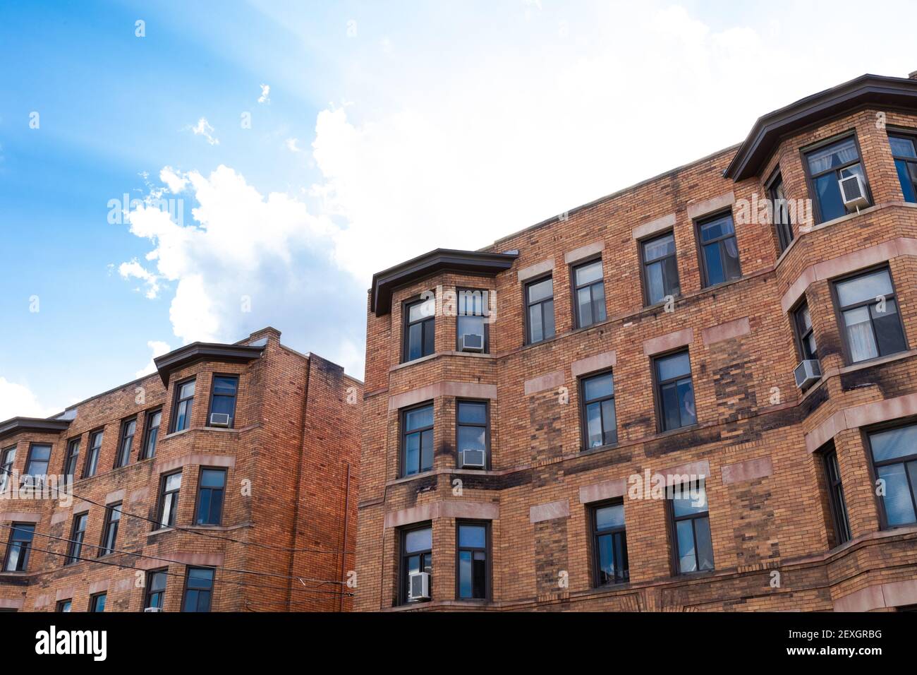 Old brick apartment buildings against bright blue sky with clouds ...