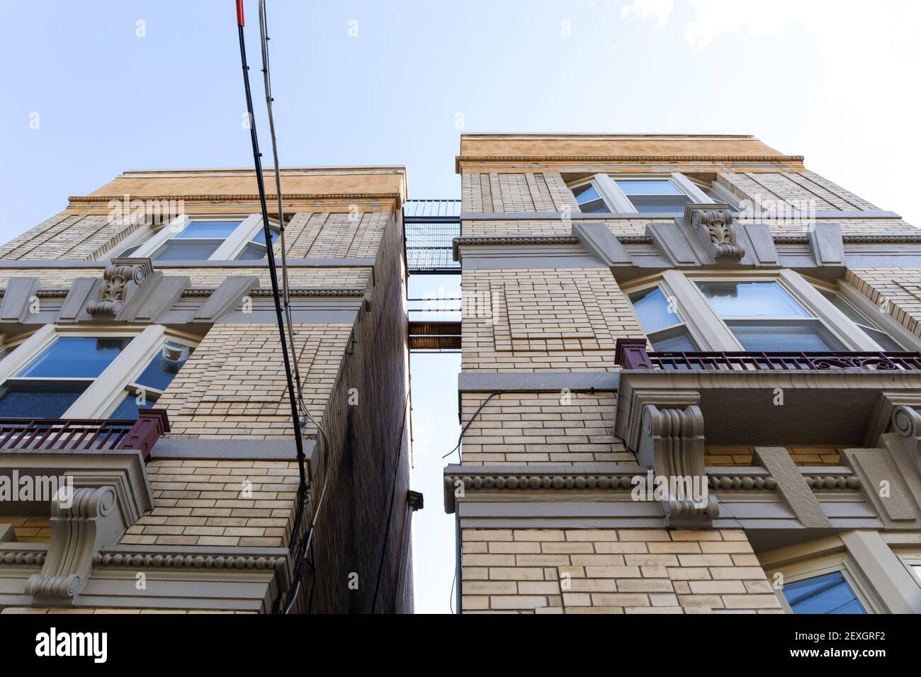 Upward view of space between two apartment buildings revealing metal ...