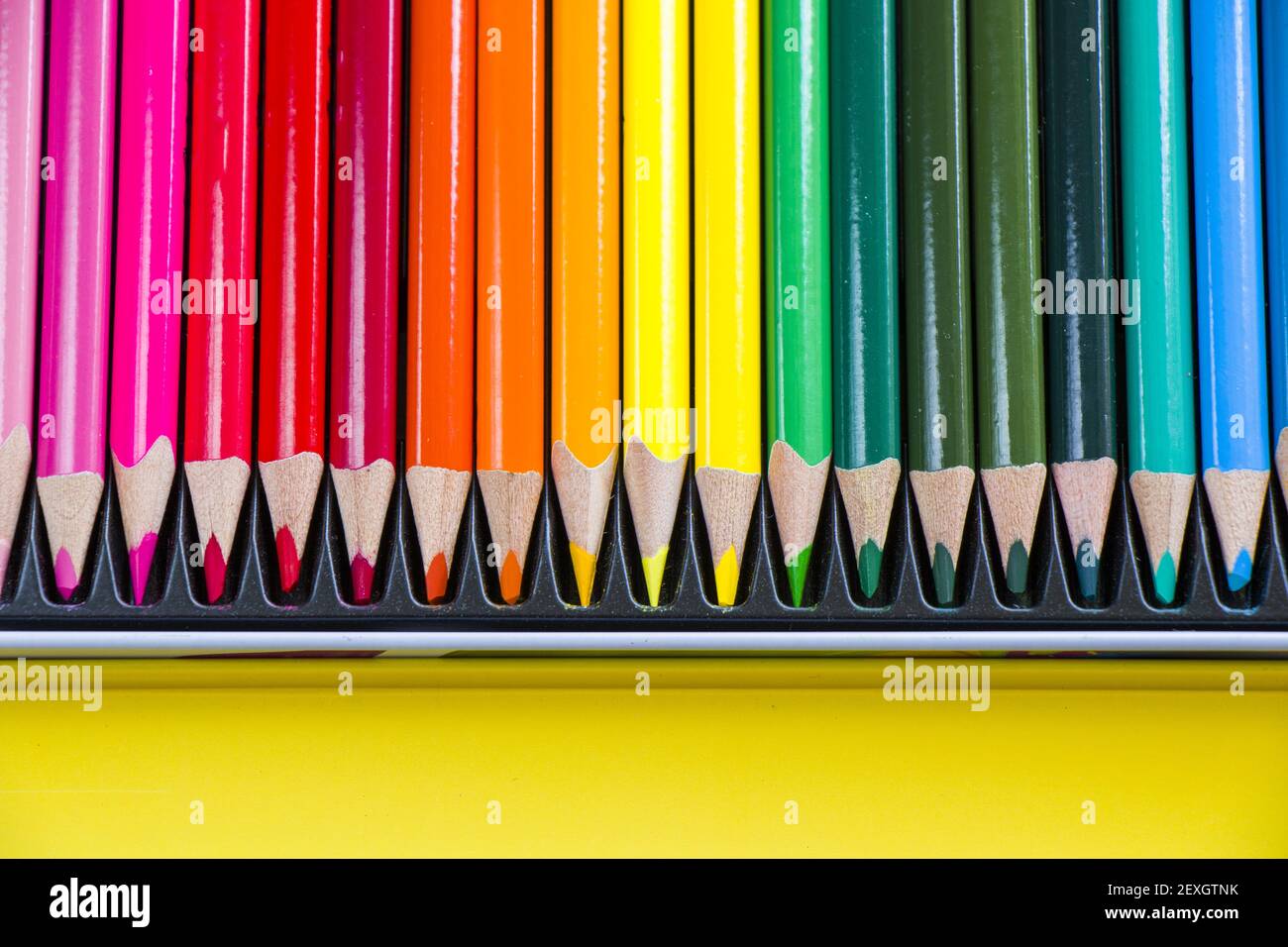 A closeup top view of multicolored color pencils in an open box with a ...
