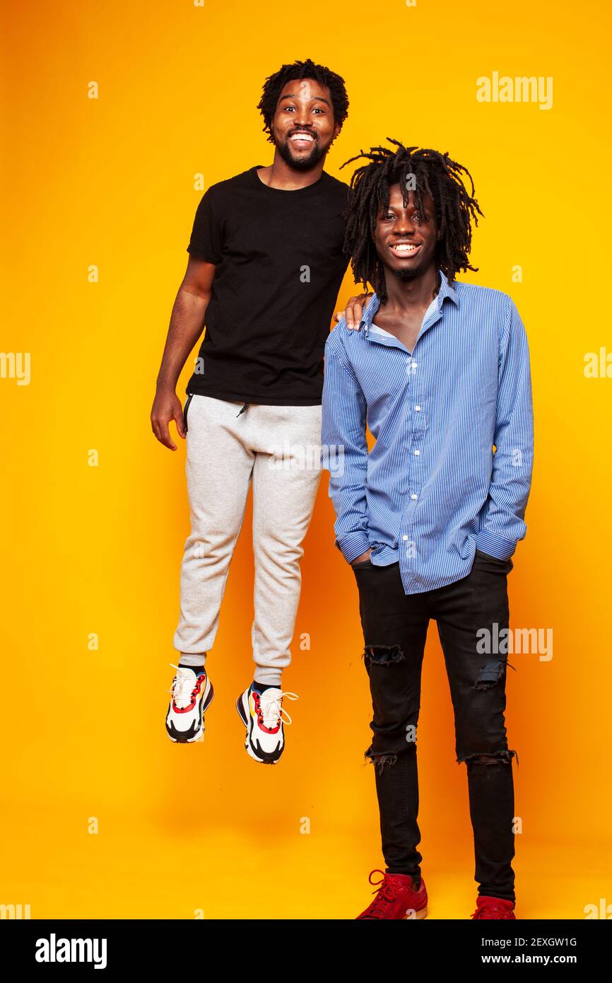 two african american guys posing cheerful together on yellow background ...