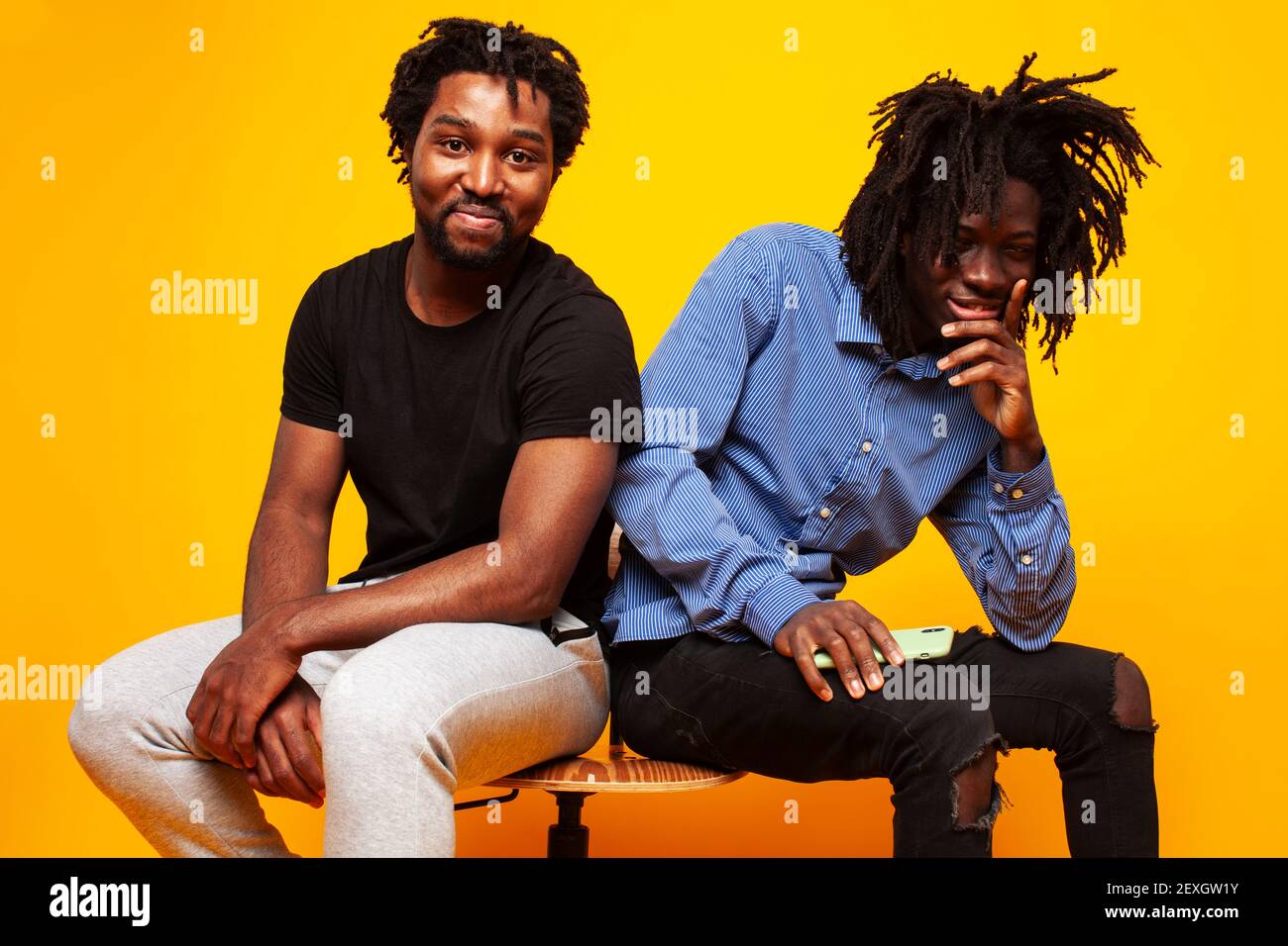 two african american guys posing cheerful together on yellow background ...