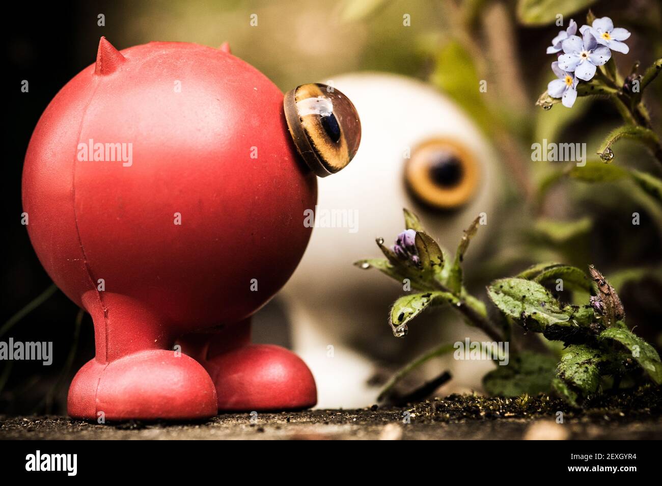 A small red round toy with one eye on a blurred background Stock Photo ...
