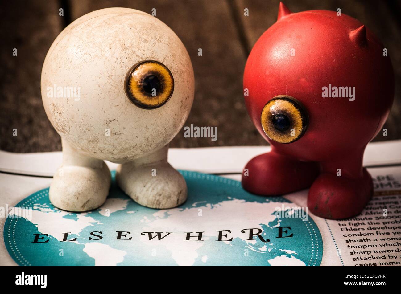 Two small red round toys with one eye on a book Stock Photo - Alamy