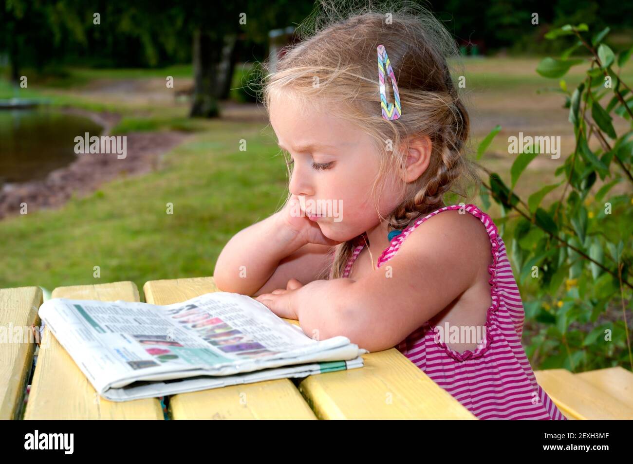 Cute little girl reading newspaper Stock Photo - Alamy