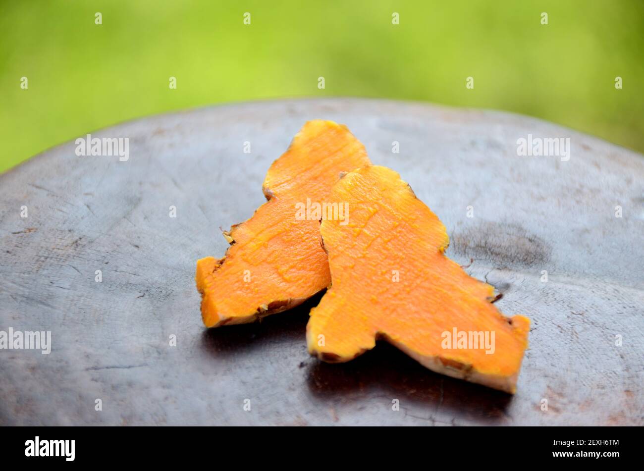 A turmeric root cut in half on a tree stump in a natural environment ...