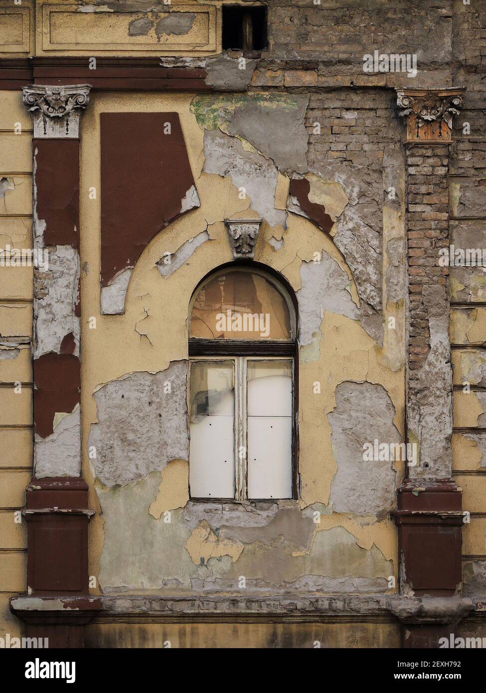 A vertical shot of an abandoned building with cracked walls and broken ...