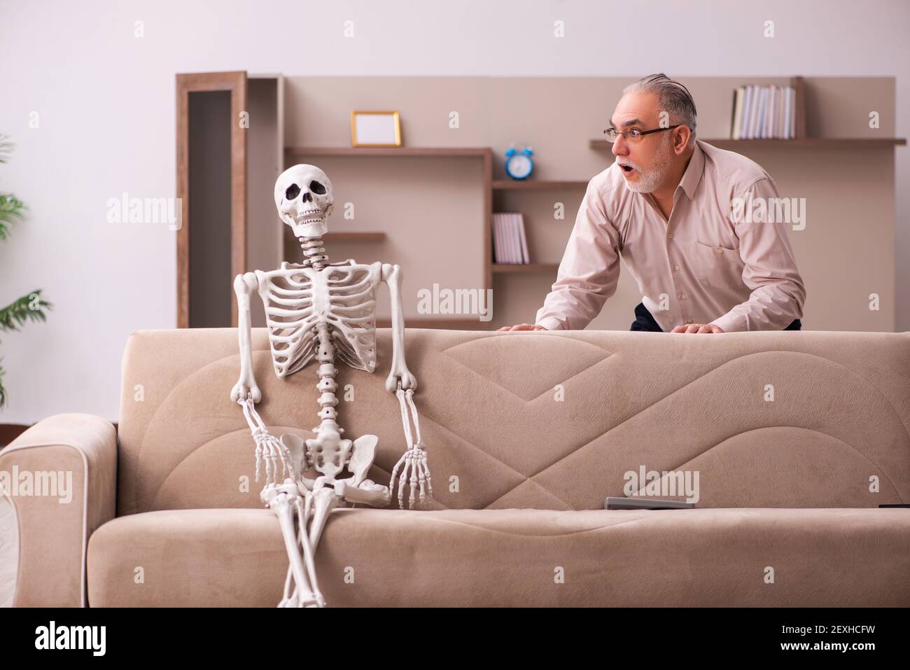 Old man sitting on the sofa with the female skeleton in undying love ...