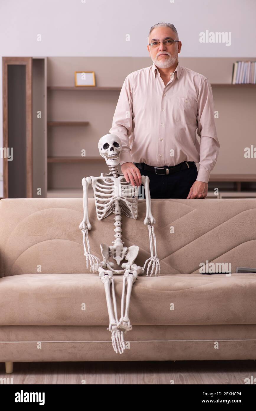Old man sitting on the sofa with the female skeleton in undying love ...