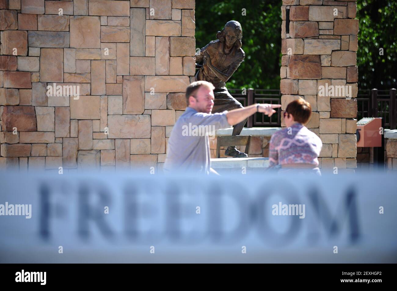 People sit in front of a life-size bronze statue of Anne Frank by ...