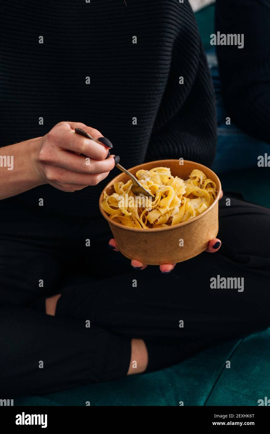 A vertical shot of a woman eating delicious pasta from a bowl Stock ...