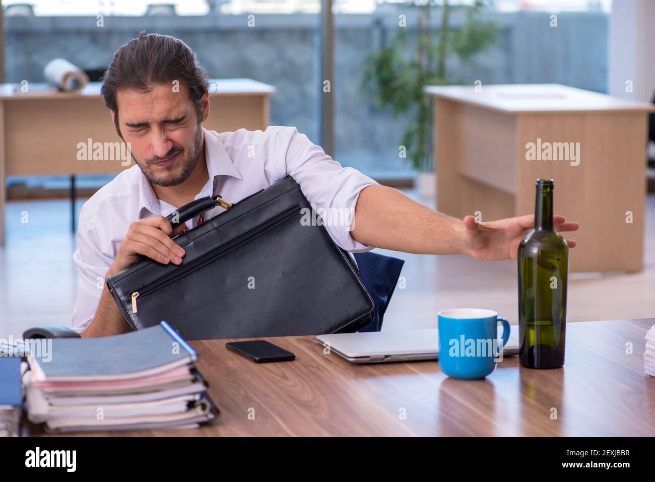 Young alcohol addicted employee working in the office Stock Photo - Alamy