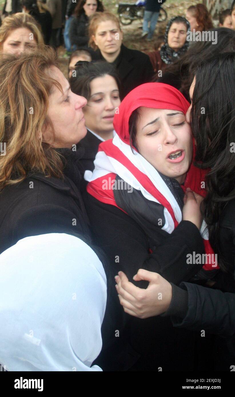 Reema Hassan, 22, a Syrian flag drapped over her head, is overcome with grief as she mourns her ...
