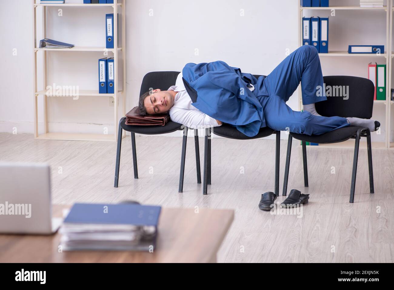 Young employee sleeping in the office on chairs Stock Photo - Alamy