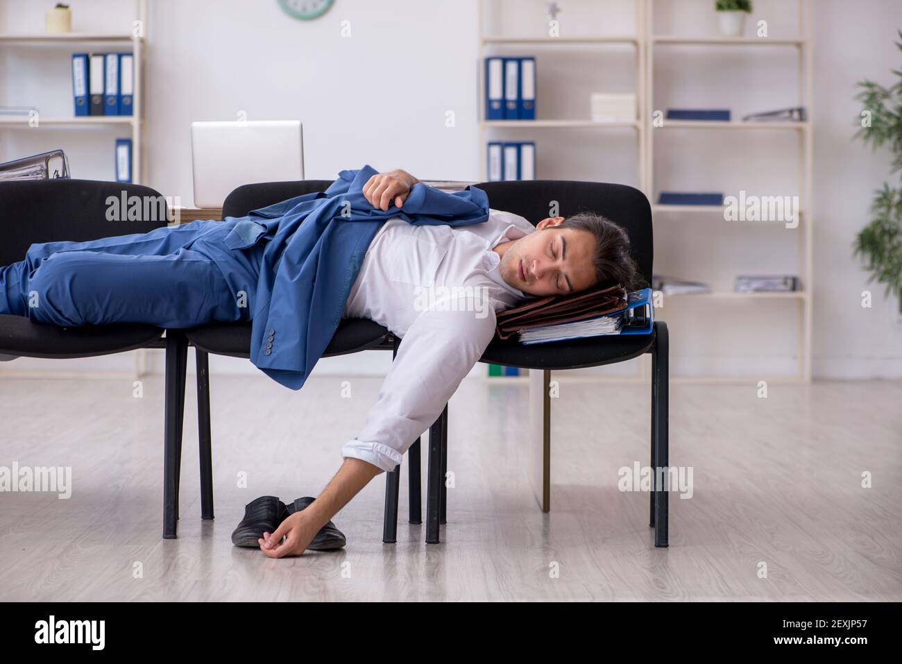 Young employee sleeping in the office on chairs Stock Photo - Alamy