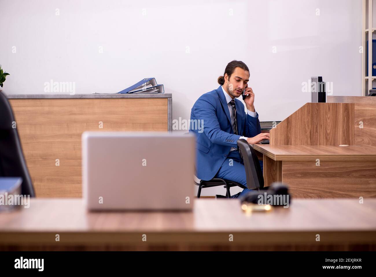 Young employee sitting at workplace Stock Photo - Alamy