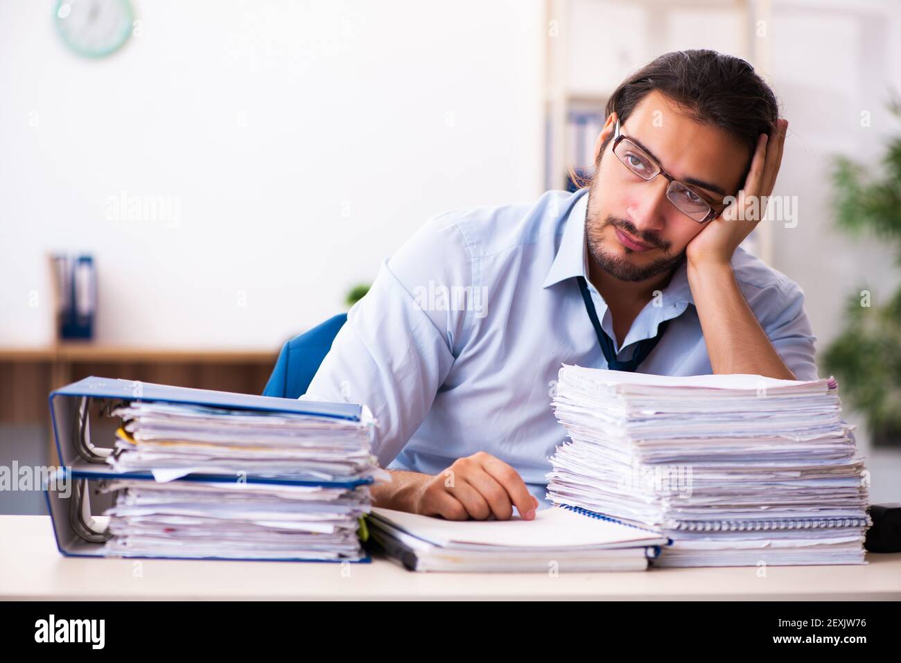 Young employee unhappy with excessive work in the office Stock Photo ...
