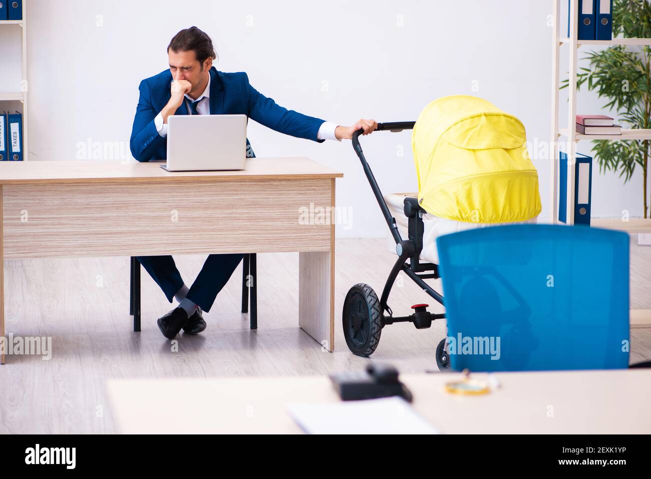Young employee looking after kid at workplace Stock Photo - Alamy