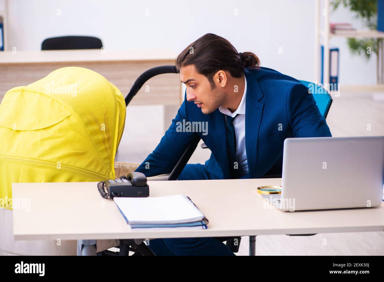 Young employee looking after kid at workplace Stock Photo - Alamy