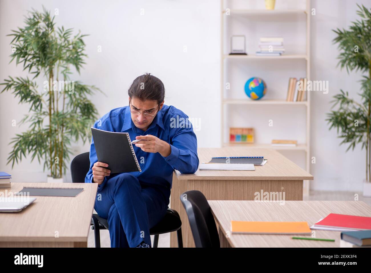 Young teacher checking notes in the classroom Stock Photo - Alamy