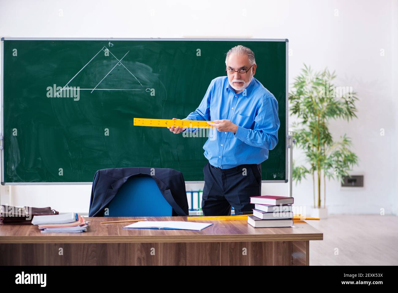 Senior male geometry teacher holding triangle Stock Photo - Alamy