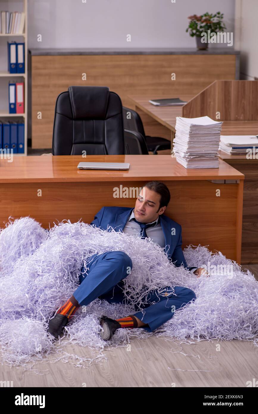 Young male employee cutting papers in the office Stock Photo - Alamy