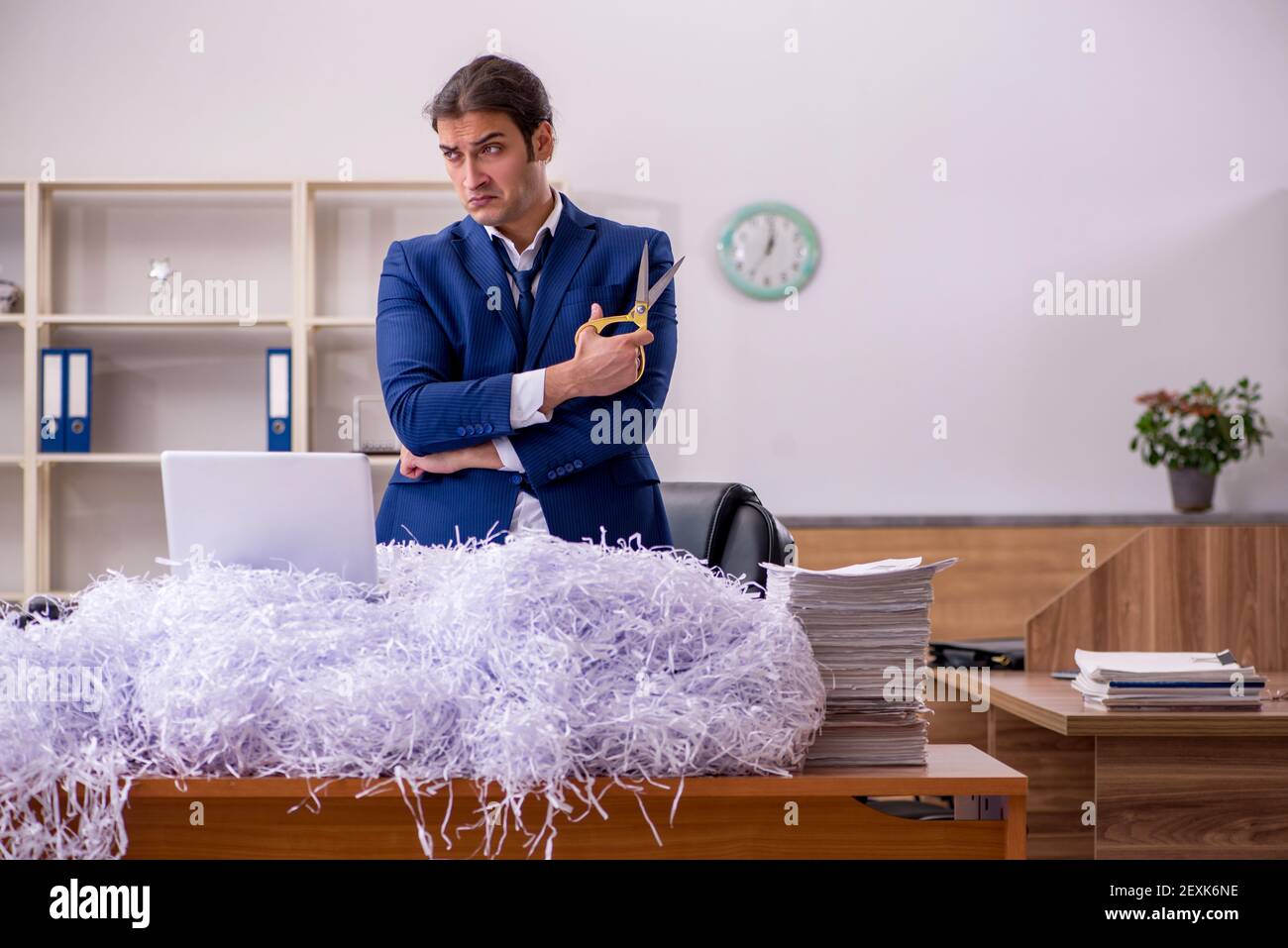 Young male employee cutting papers in the office Stock Photo - Alamy