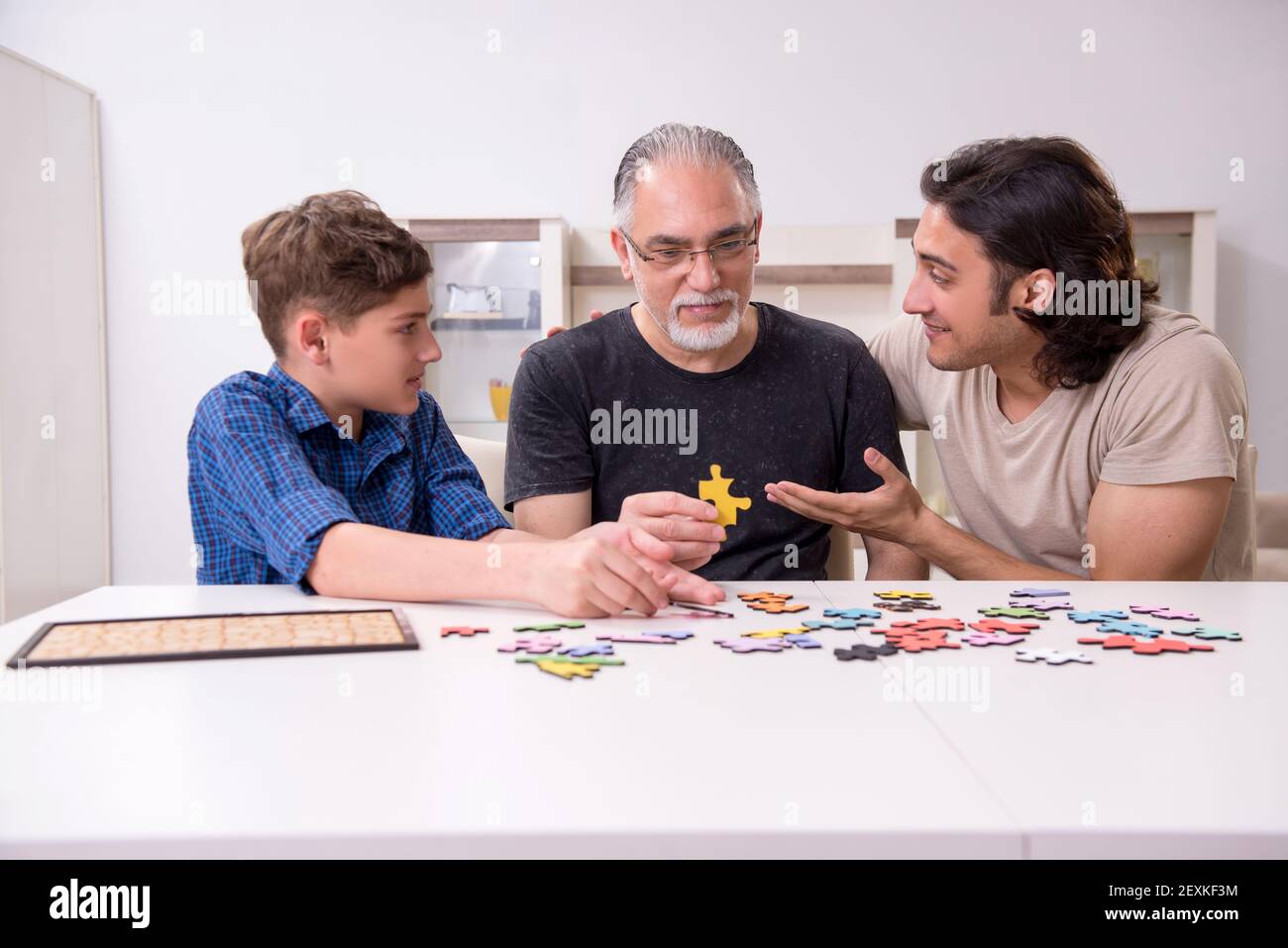Three generations of family playing jigsaw puzzle Stock Photo - Alamy