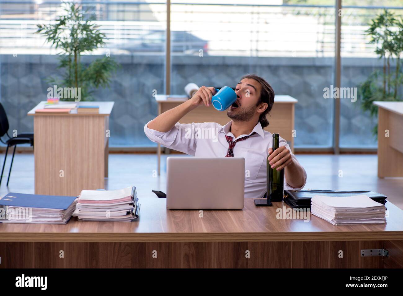 Young alcohol addicted employee working in the office Stock Photo - Alamy