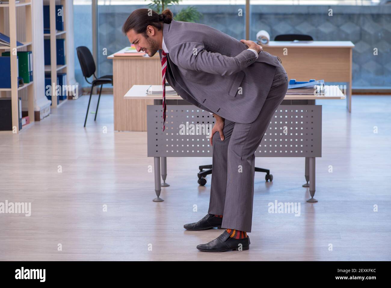 Young employee doing sport exercises at workplace Stock Photo - Alamy