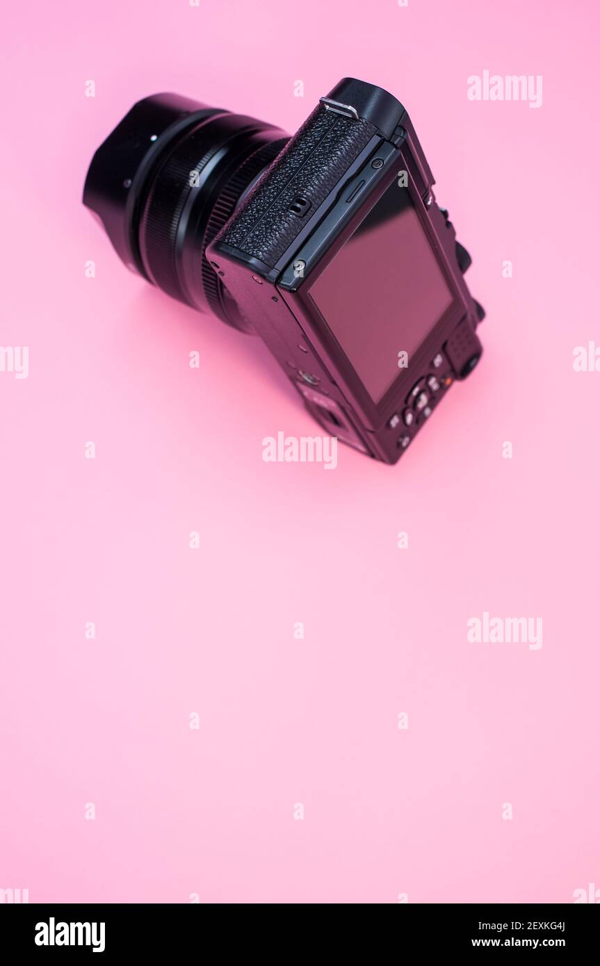 A vertical shot of a camera on a pastel pink background for a copy ...