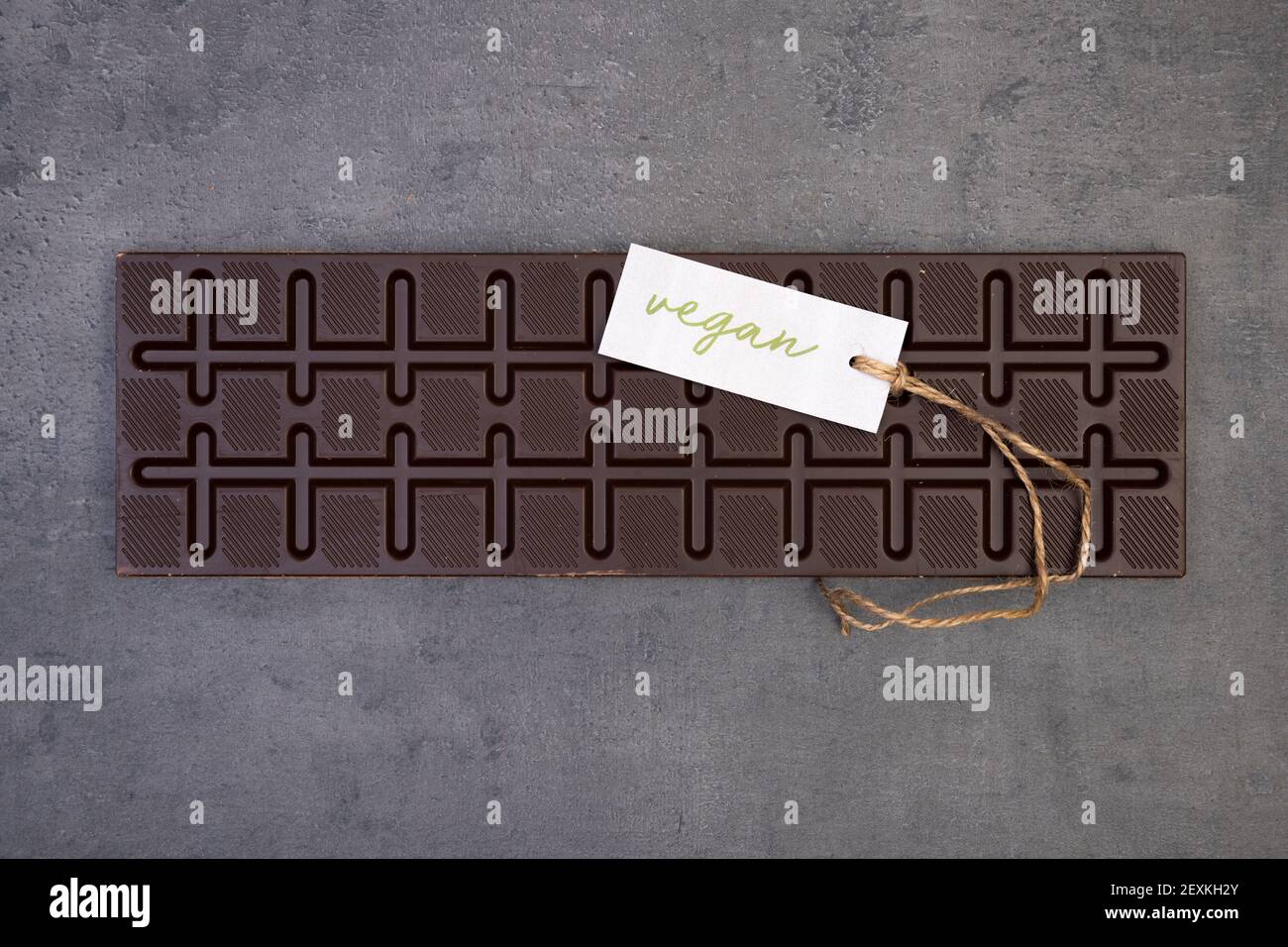 sweet bar of chocolate lies on a gray stone background with a label ...