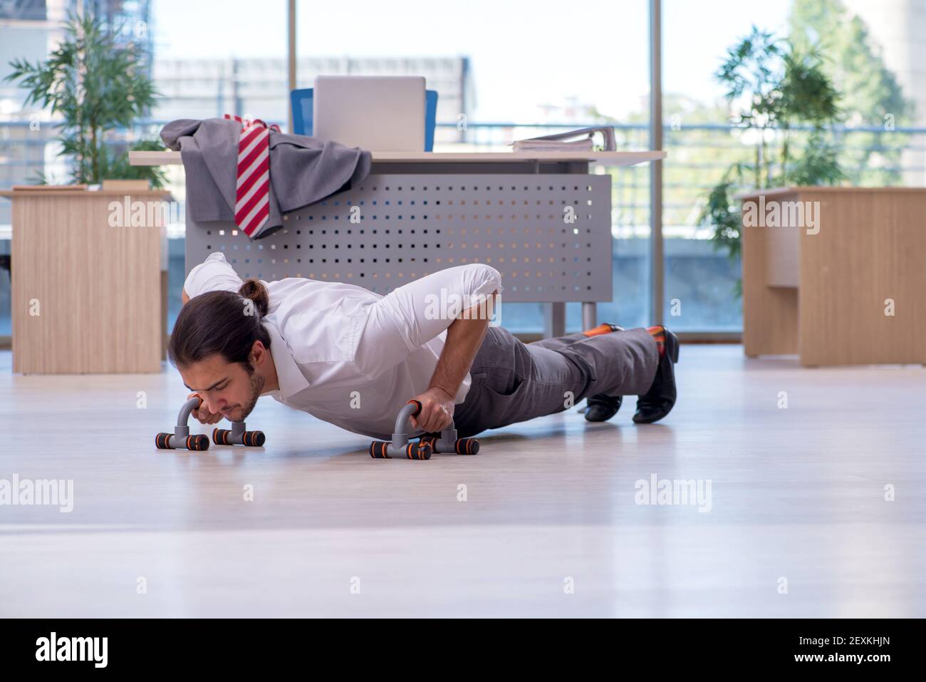 Young employee doing sport exercises at workplace Stock Photo - Alamy