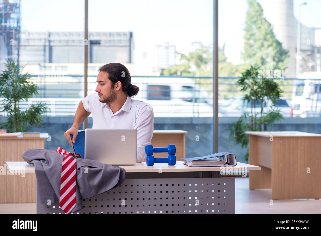 Young employee doing sport exercises at workplace Stock Photo - Alamy