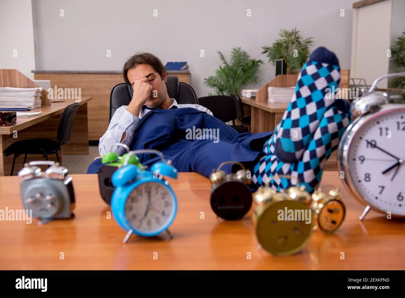 Young businessman sleeping in the office in time management concept ...