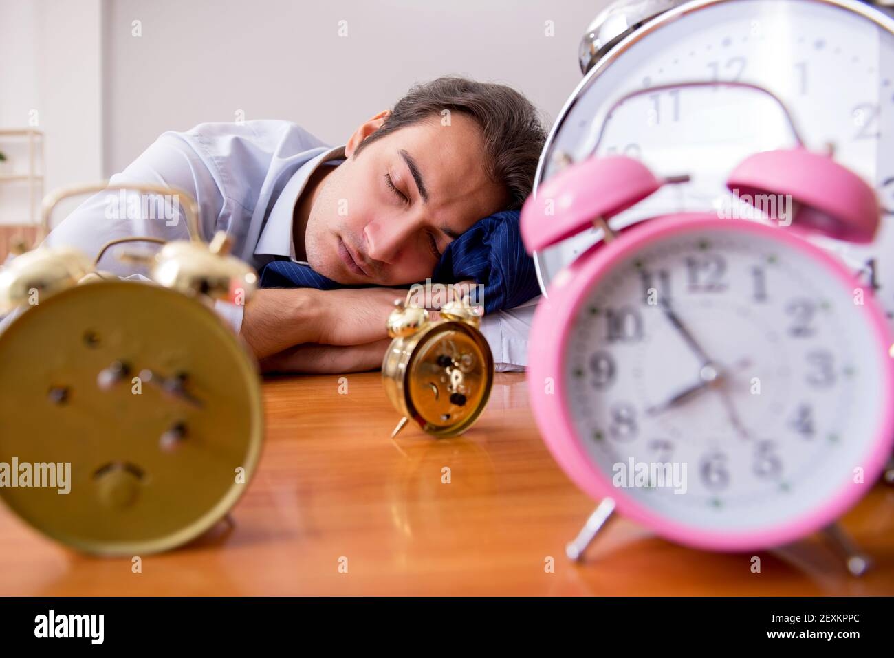 Young businessman sleeping in the office in time management concept ...