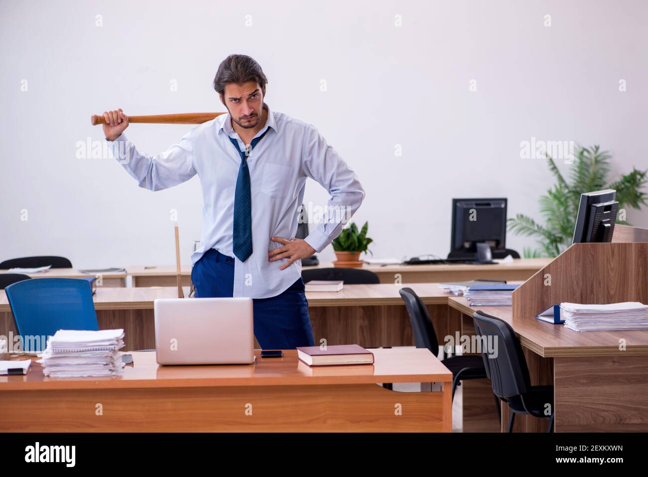Young furious employee holding baseball bat in the office Stock Photo ...
