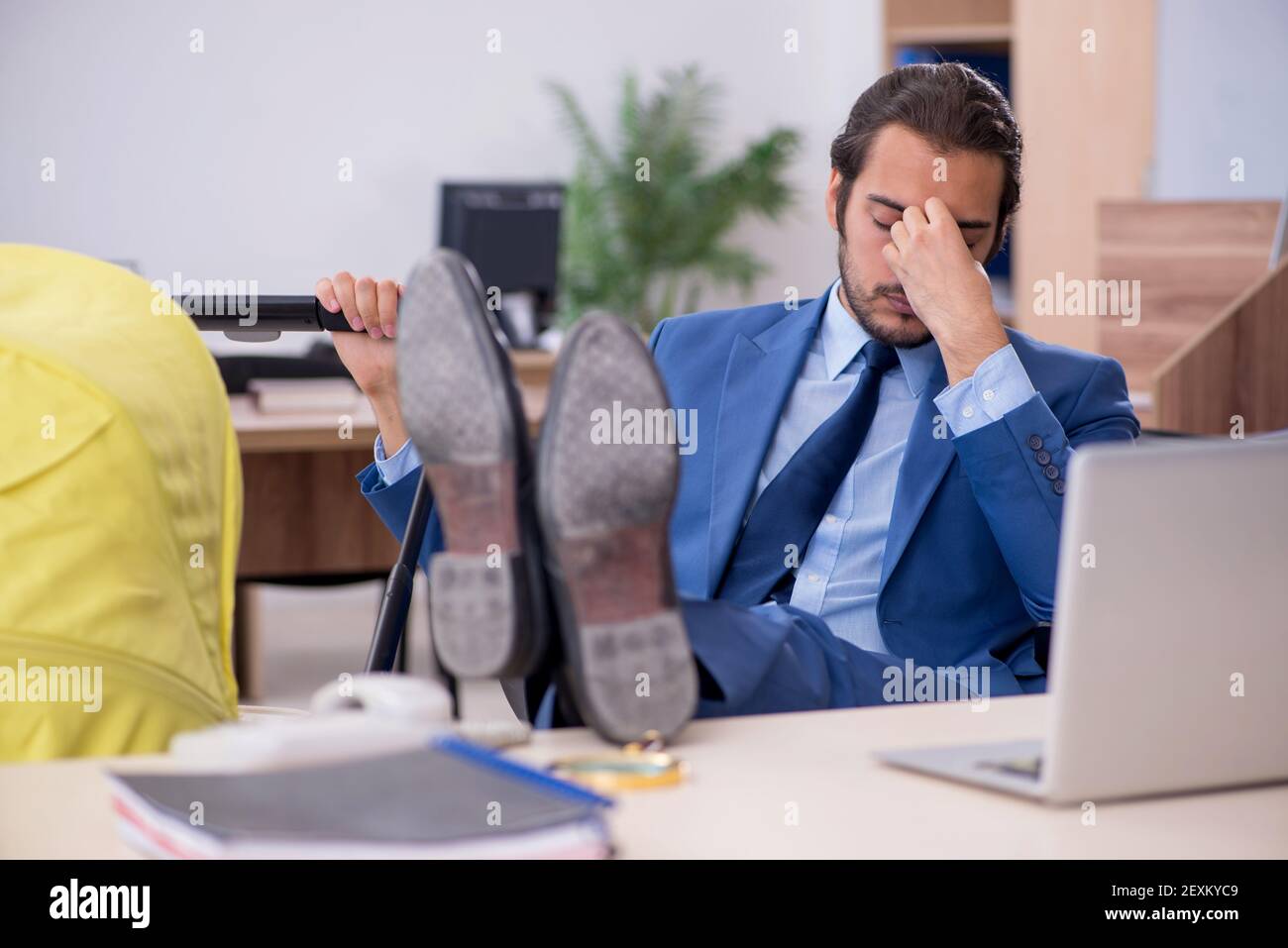 Young male employee looking after new born in the office Stock Photo ...