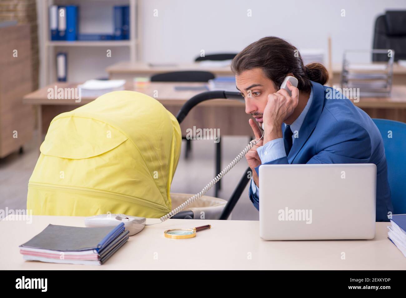 Young male employee looking after new born in the office Stock Photo ...