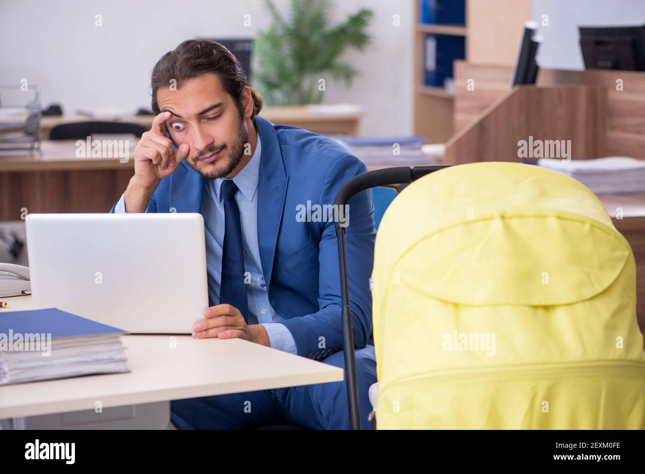 Young male employee looking after new born in the office Stock Photo ...