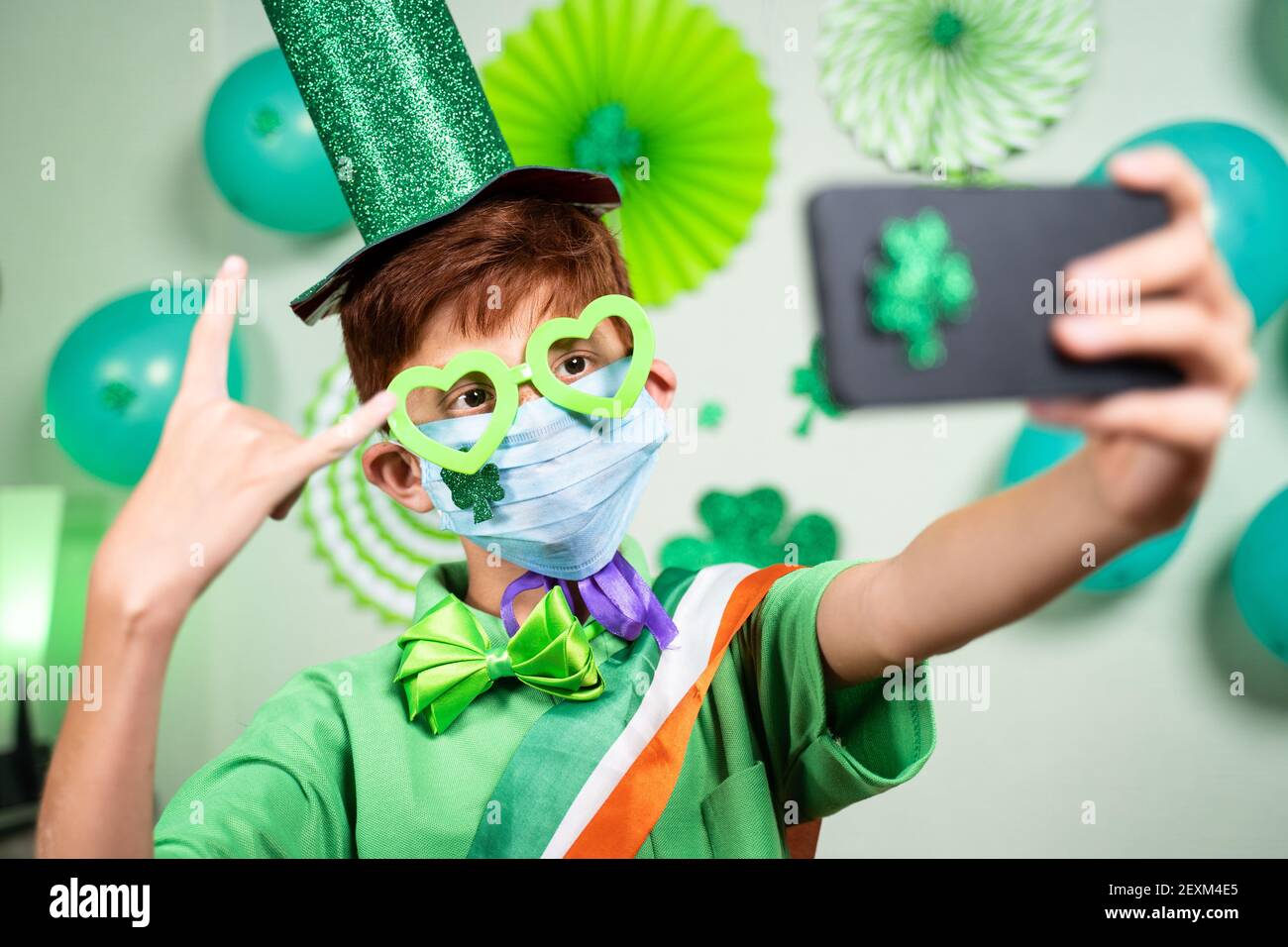Young kid with medical face mask taking selfie during Saint patricks ...