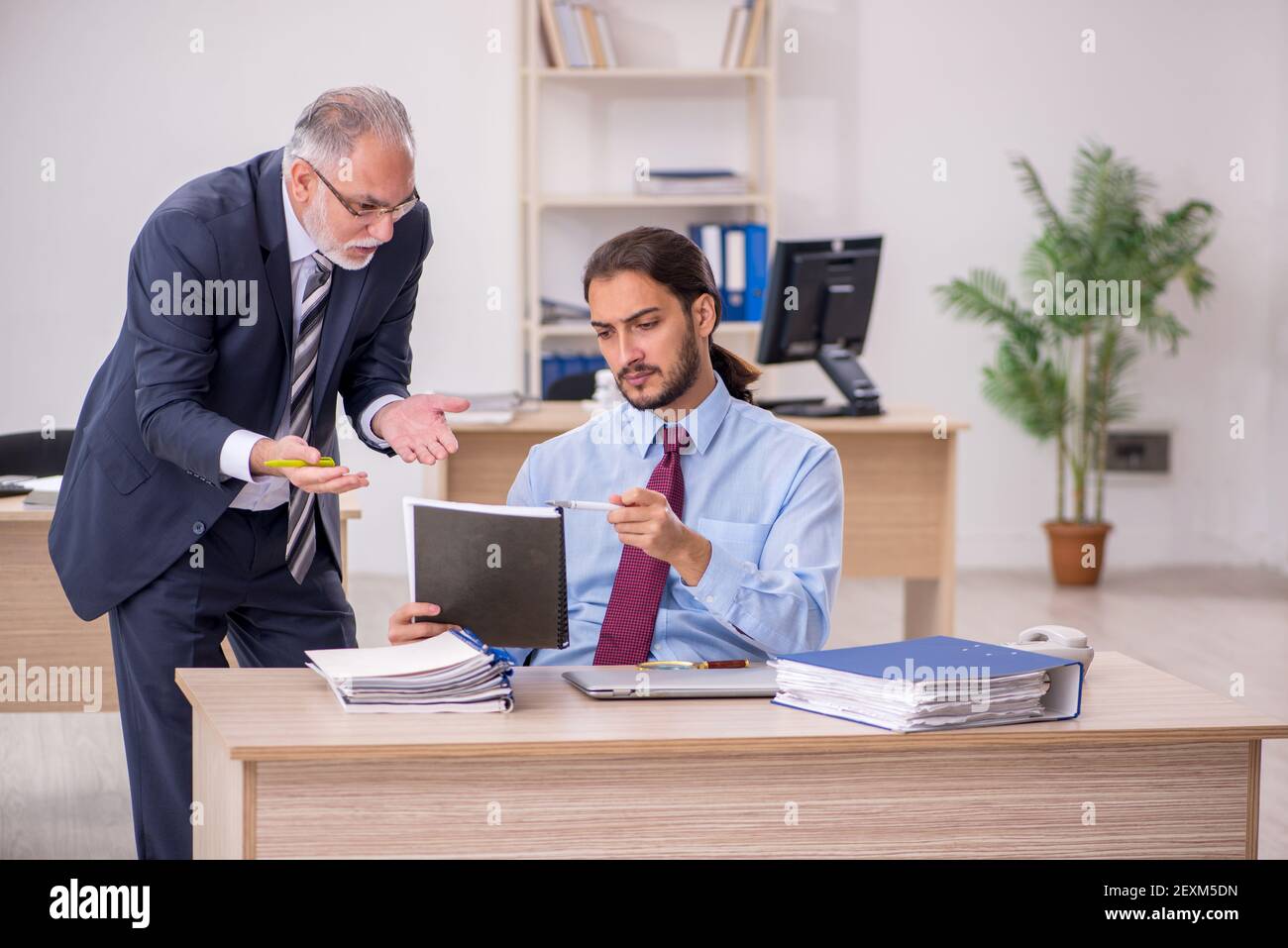 Old boss and young employee working in the office Stock Photo - Alamy