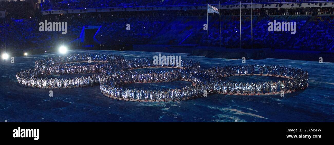 Performers dressed in mirrored costumes form the Olympic Rings, during ...
