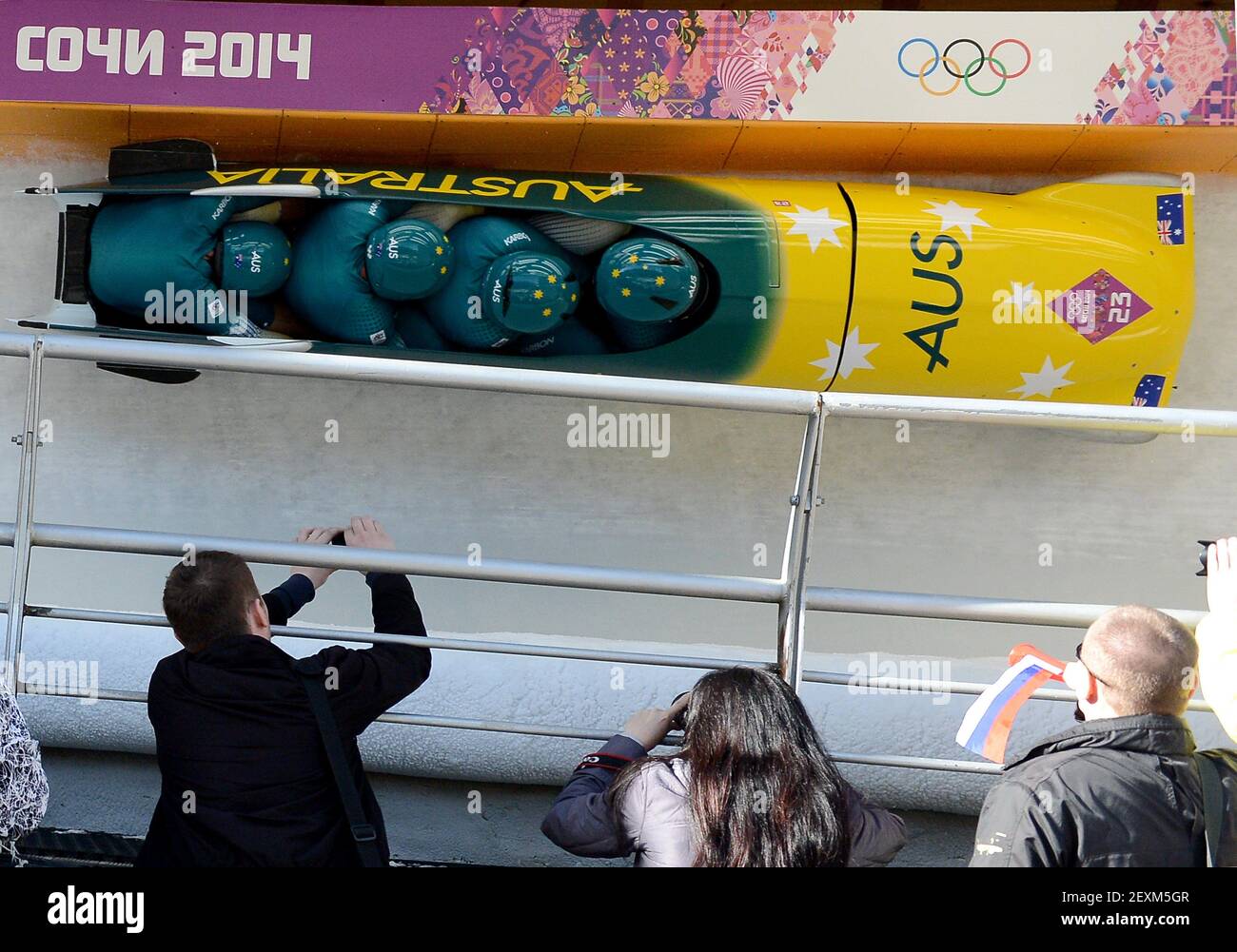 Spectators try to take a photo of the Australia 1 bobsled as it passes ...