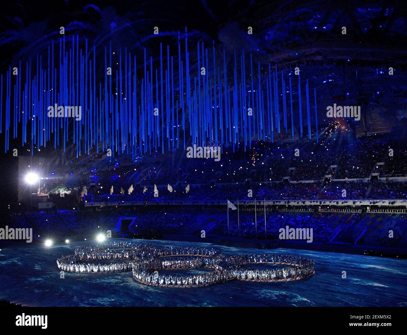 Performers dressed in mirrored costumes form the Olympic Rings, during ...