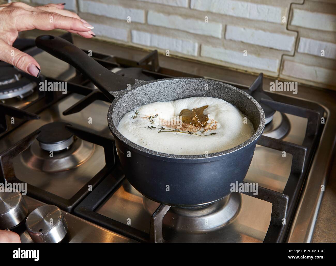Sauce in a saucepan of cream, garlic, bay leaves and nuts, boiling on a ...
